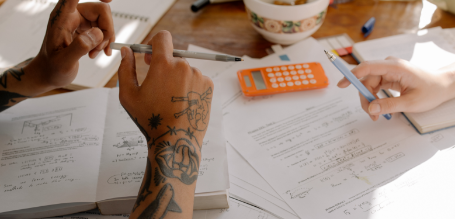 A cropped photo of students with documents scattered in front of them.